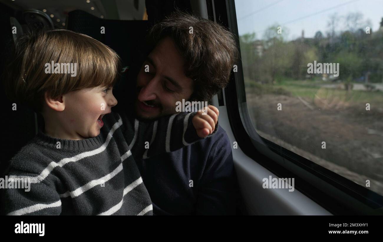 Parent and child traveling by train together. Father and son staring at ...