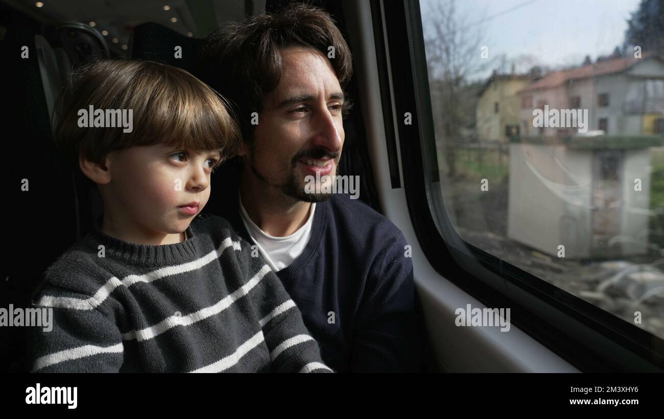 Parent and child traveling by train together. Father and son staring at ...