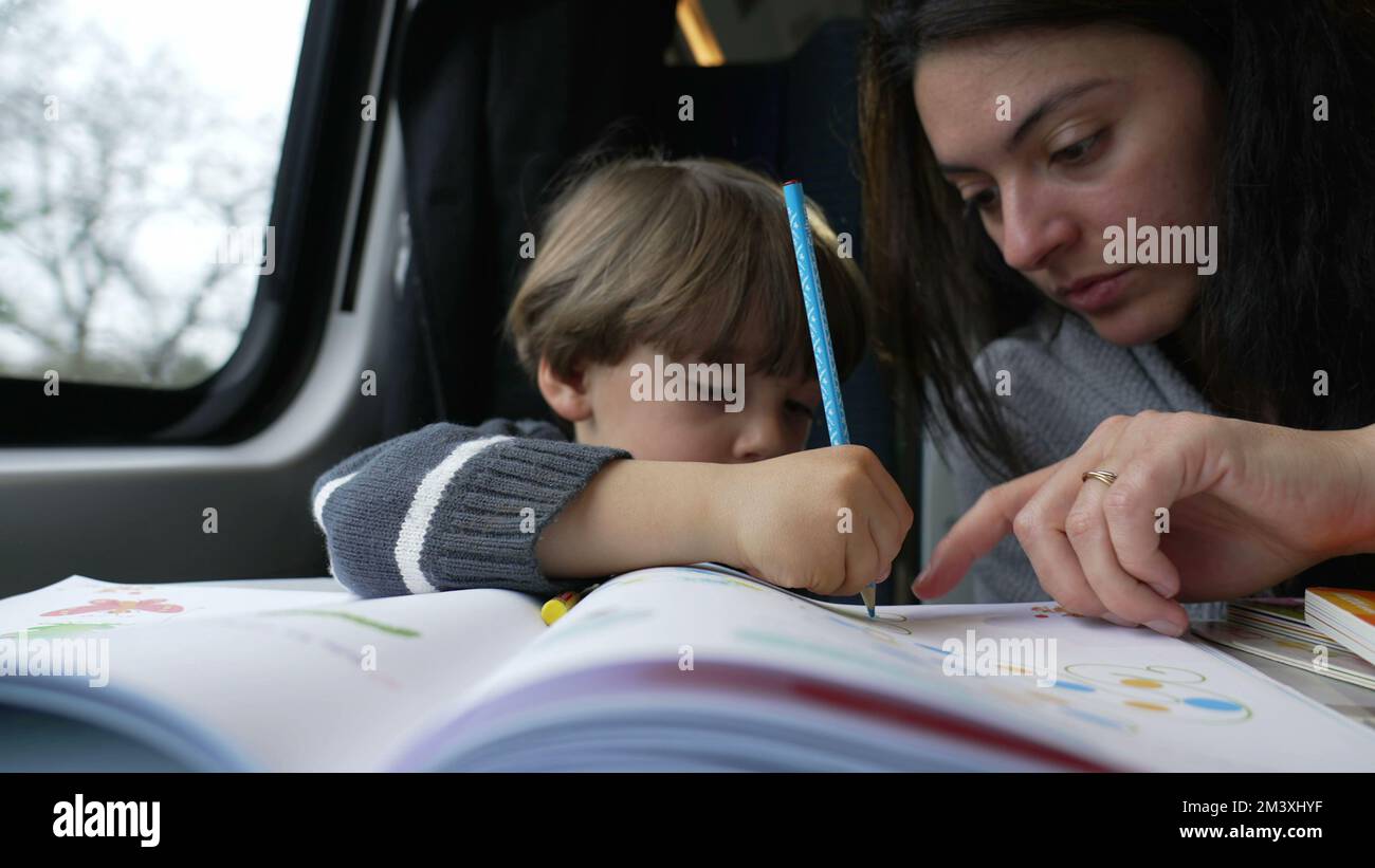 Small child doing homework while traveling by train with mother help ...