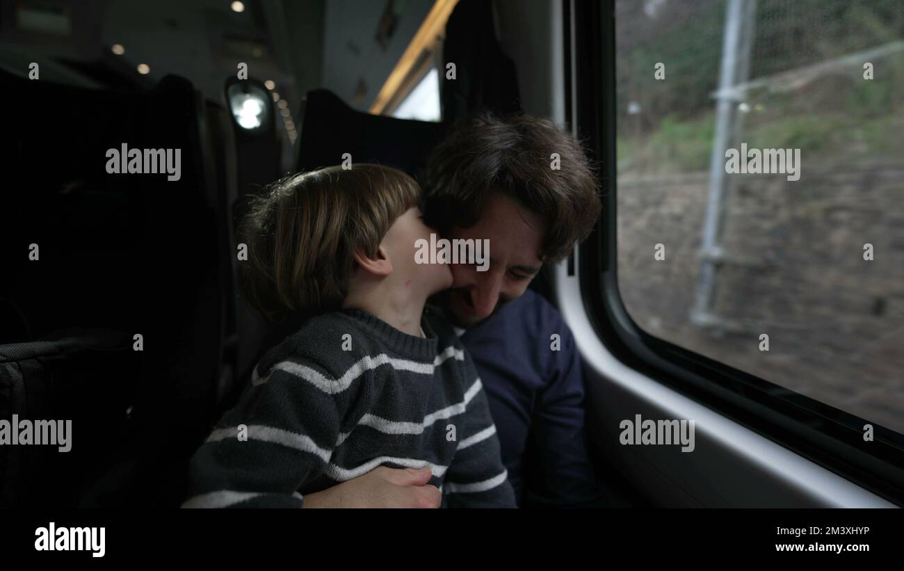 Son kissing father on cheek while traveling by train. Parent and child ...