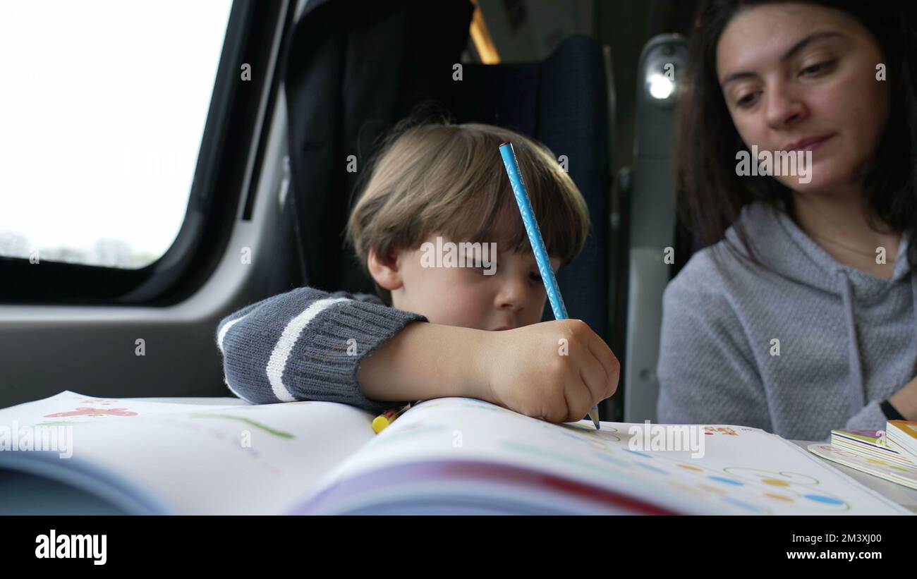 Small child doing homework while traveling by train with mother help ...