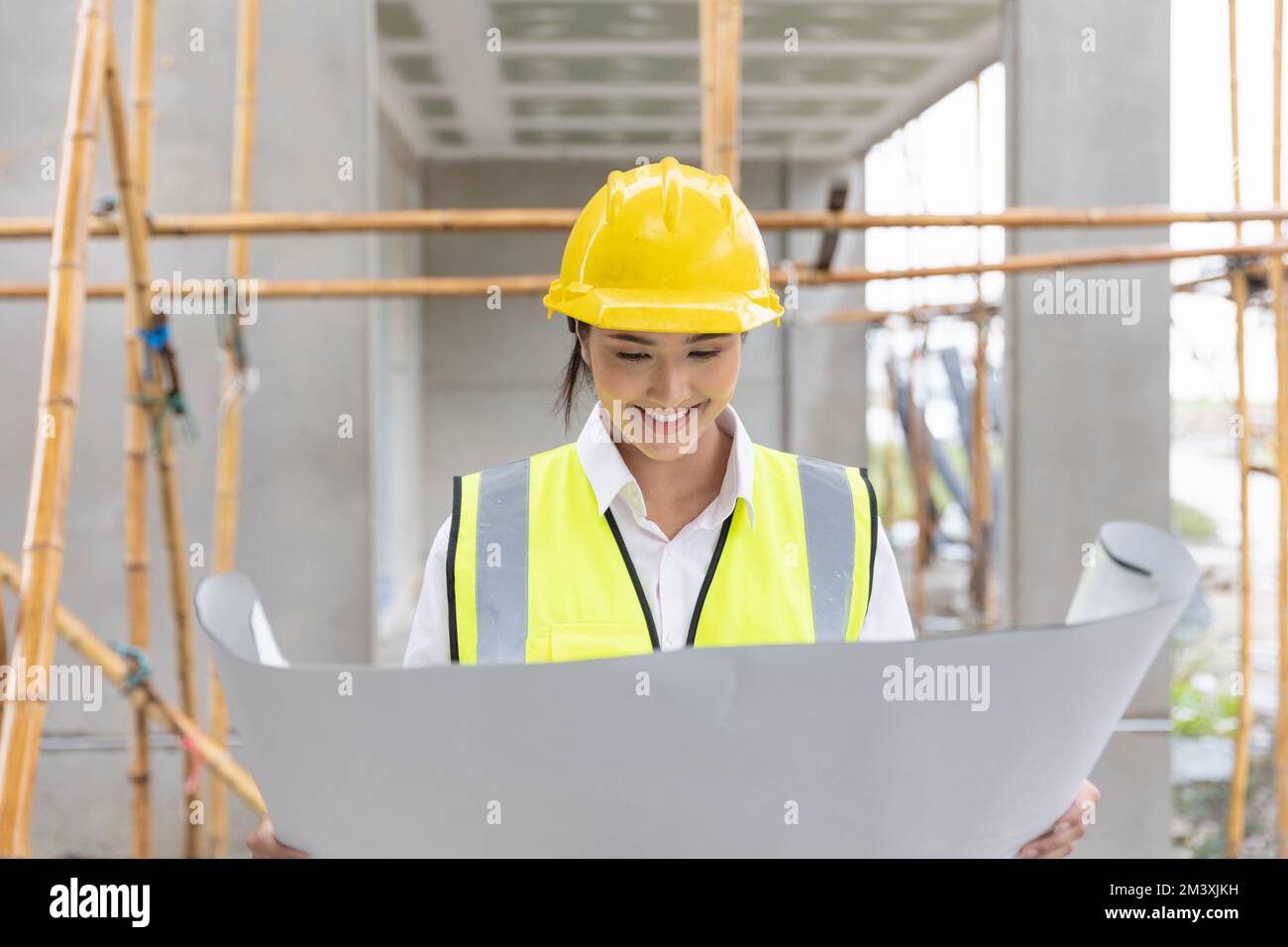 Woman builder with floor plan looking construction blueprint happy ...