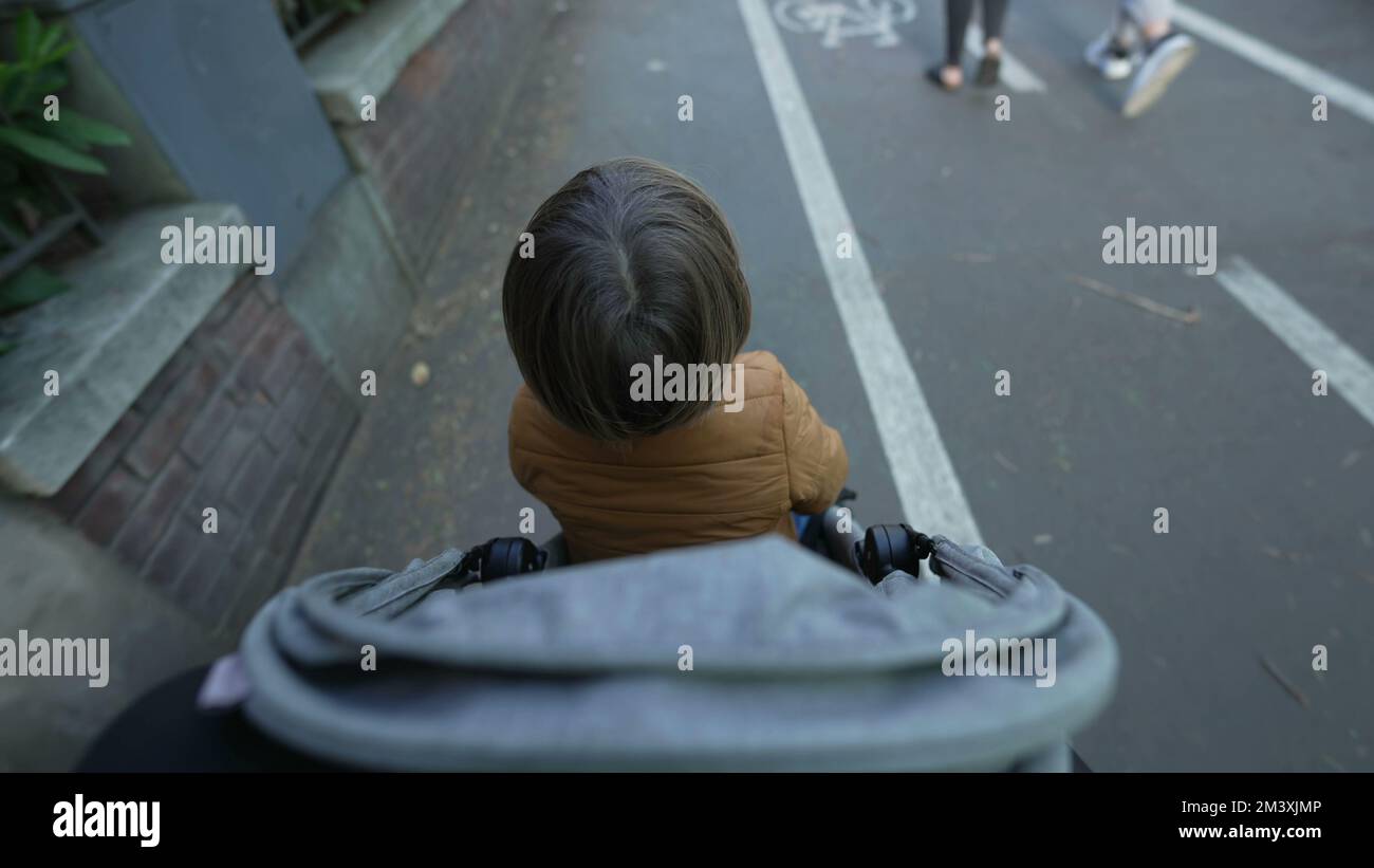 Child sitting in stroller. Parent POV walking in city street with ...