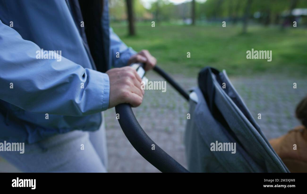 Closeup mother hands pushing baby carriage outside at park. Motherhood ...