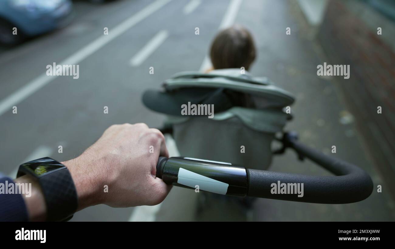 Father hand POV pushing baby carriage. Parent pushes stroller outside ...