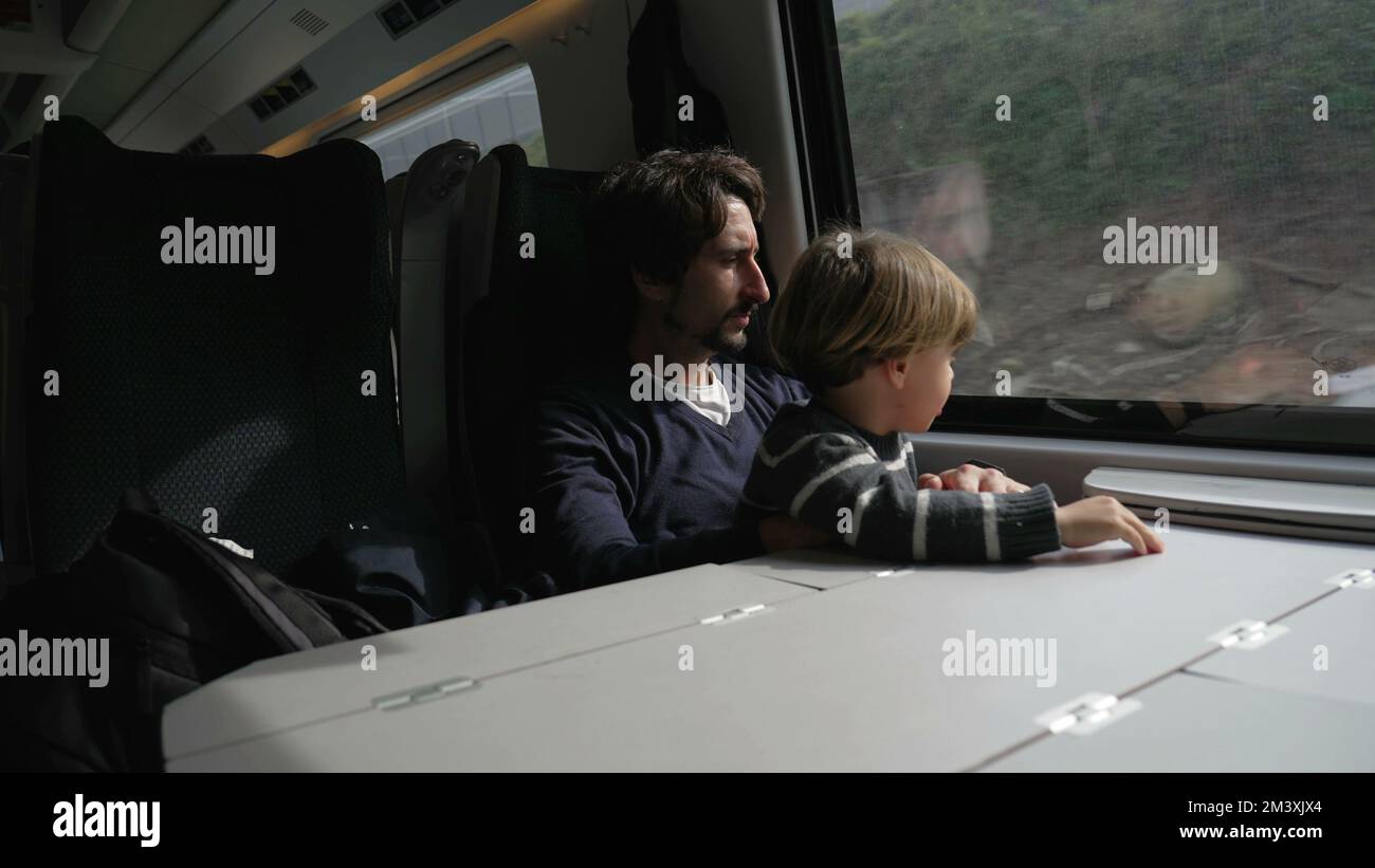 Father and son traveling by train together. Passengers seated by high ...