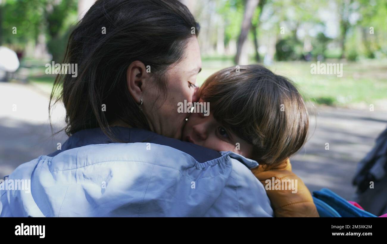 Mother kidding son on cheek sitting at park bench. Tired child waking ...