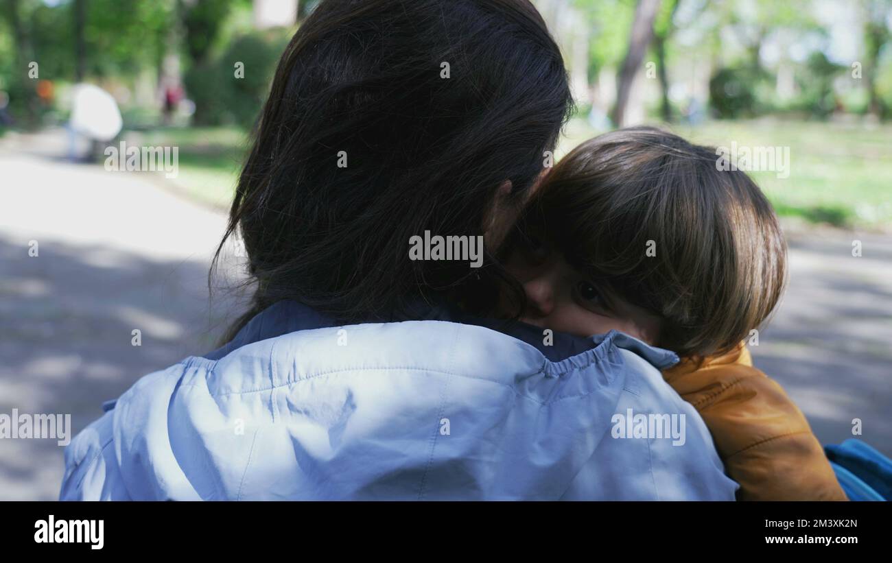 Mother kidding son on cheek sitting at park bench. Tired child waking ...