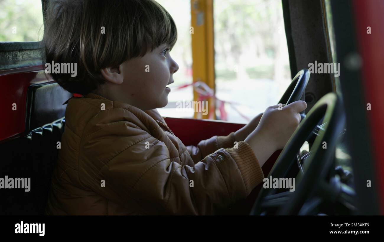 One happy small boy driving toy car interior at amusement park carousel ...
