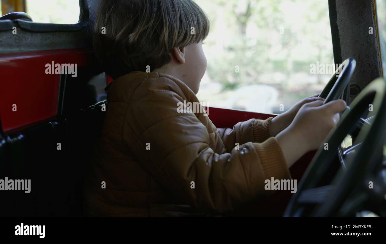 One happy small boy driving toy car interior at amusement park carousel ...