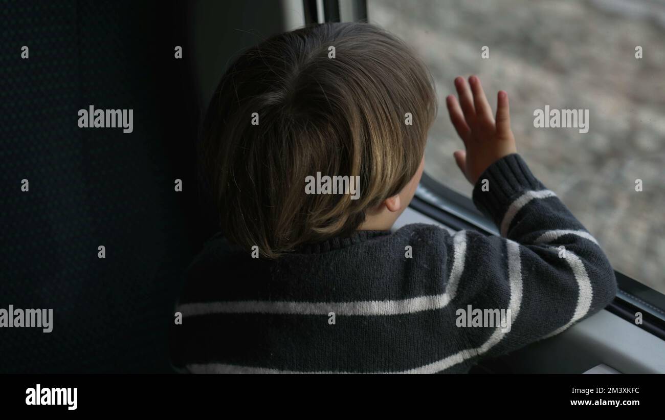 One happy child traveling on high speed train staring out window. Back ...