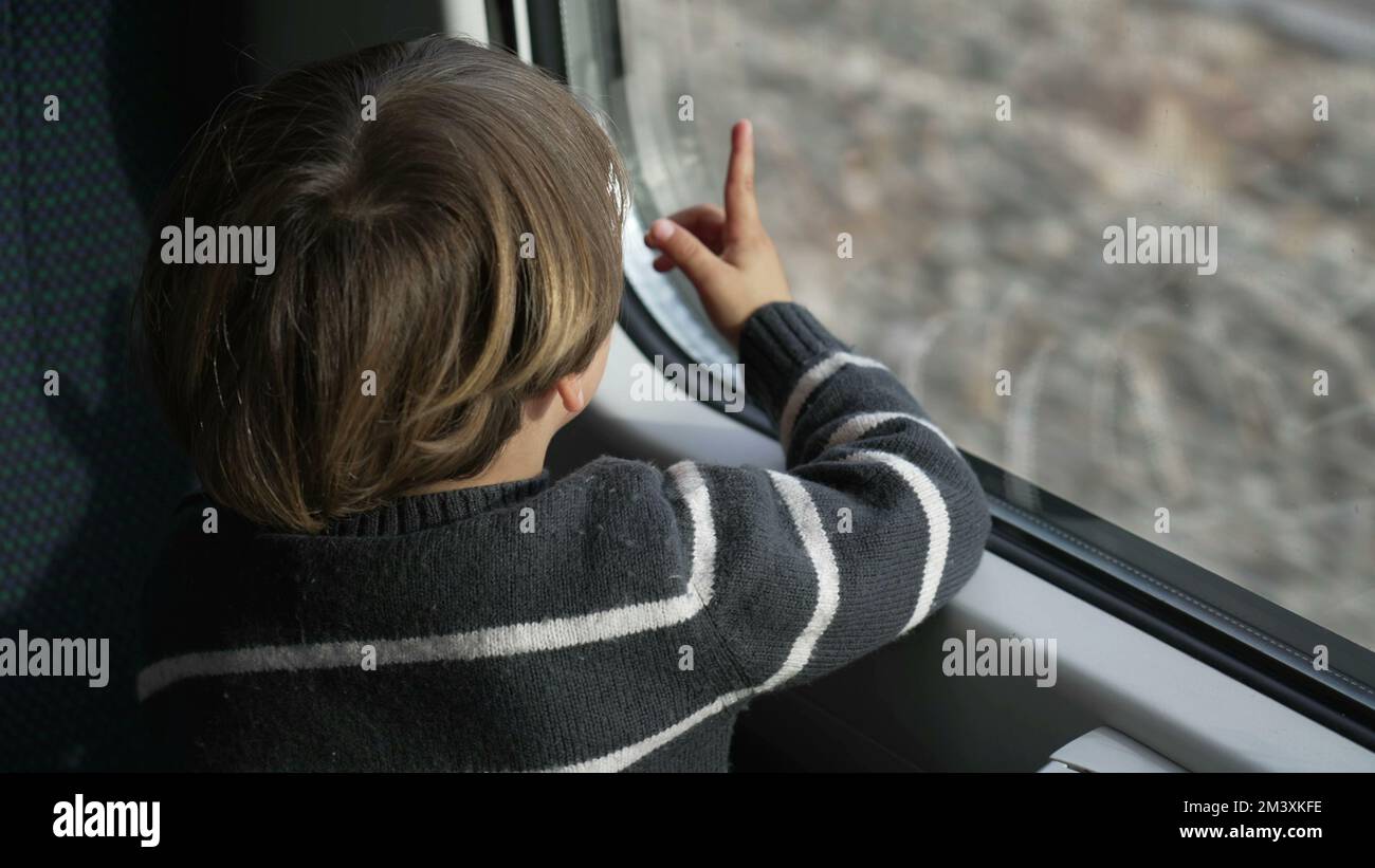 One happy child traveling on high speed train staring out window. Back ...