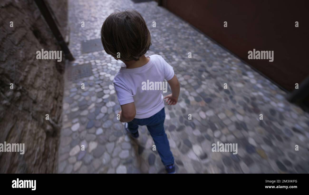 One happy small boy running on cobblestone European street in Italian ...