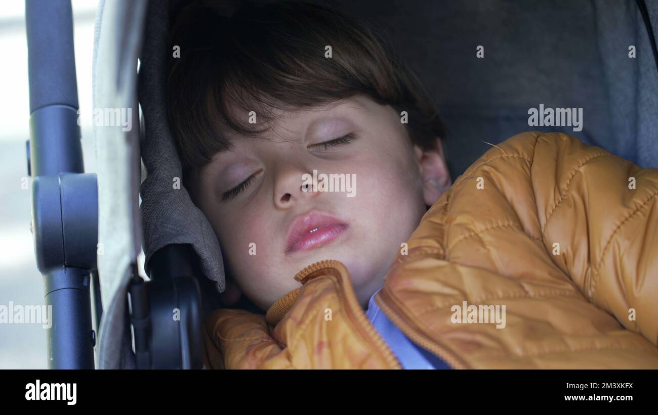 One little boy asleep sitting in stroller. Closeup child face sleeping ...