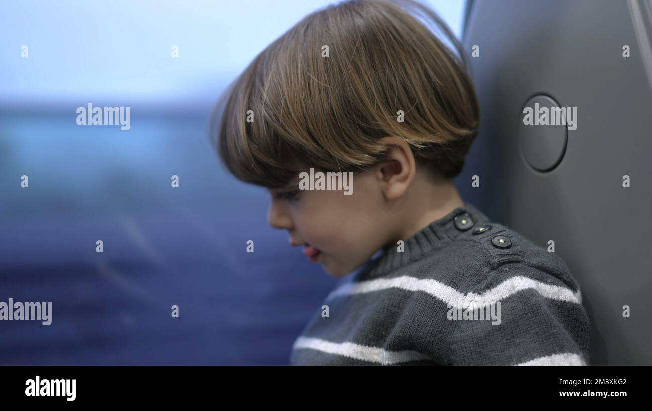 One small boy traveling by train staring at window with landscape ...