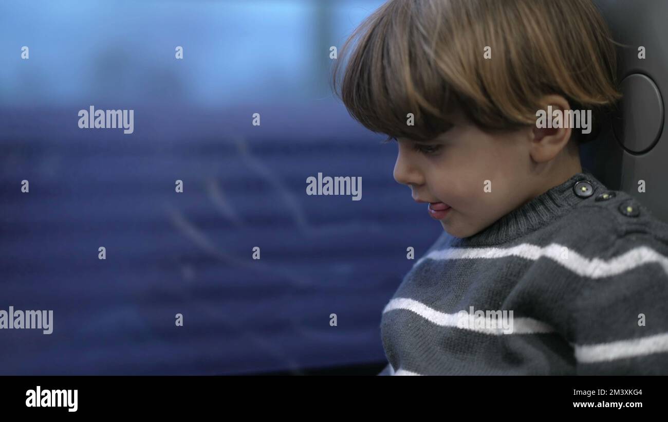 One small boy traveling by train staring at window with landscape ...