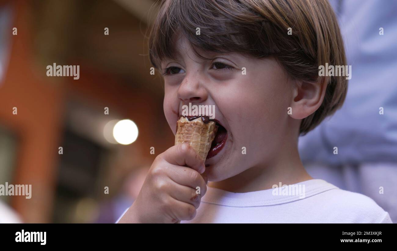 Small boy enjoying ice cream dessert outside in street. Portrait face ...
