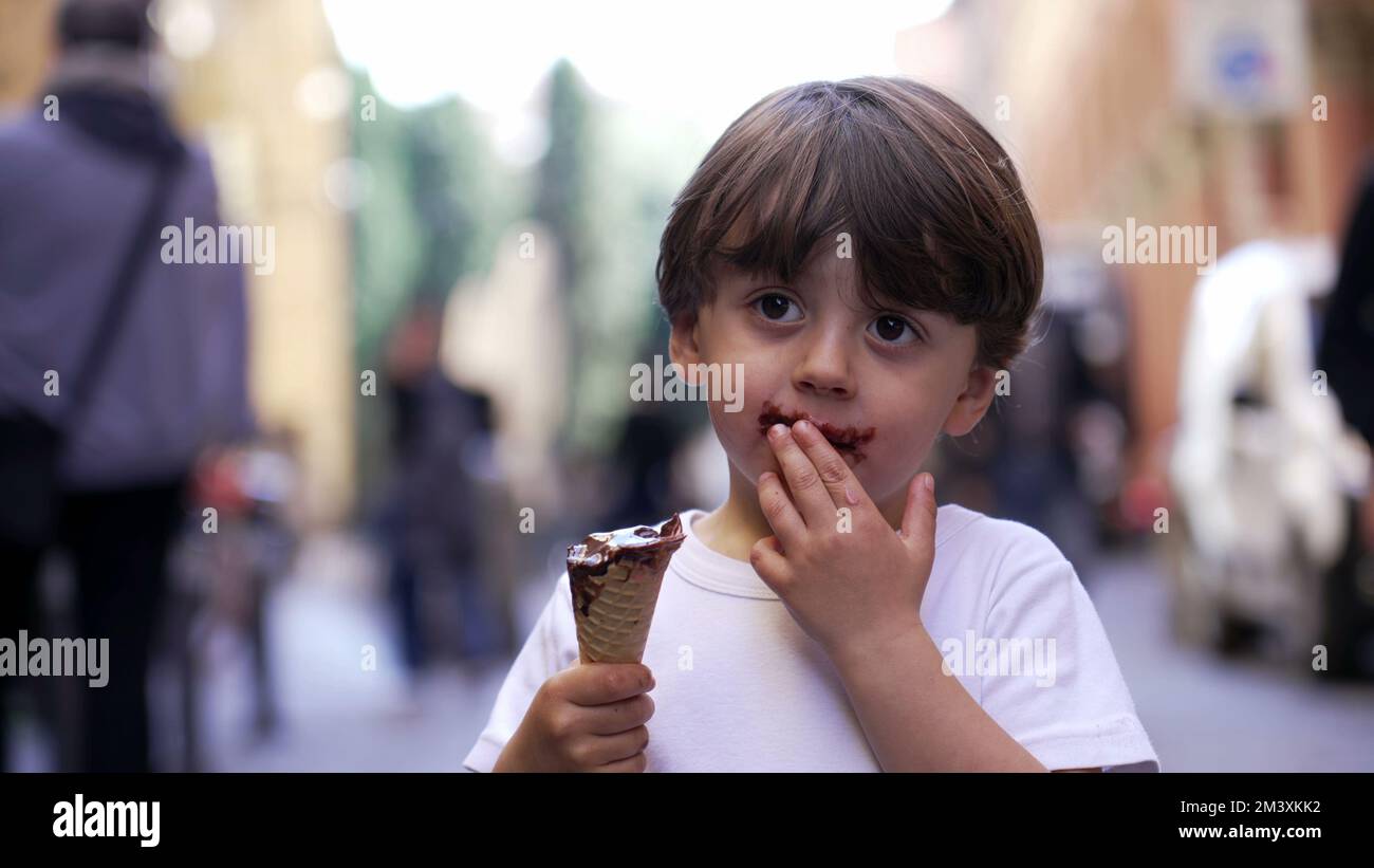 Young boy eating ice cream cone outside. Child eats italian gelato ...