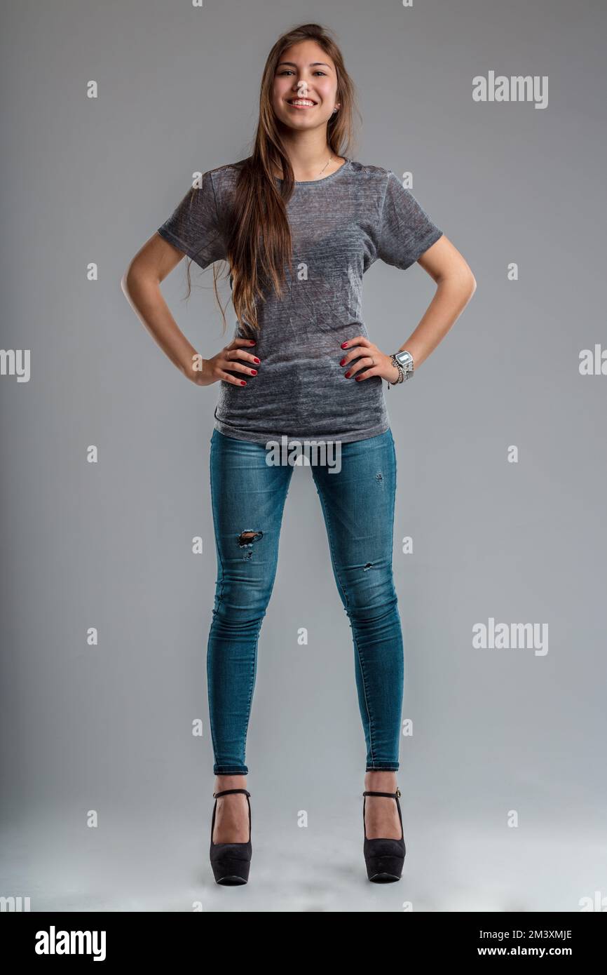 Full-length frontal portrait of girl with her hands on her hips; she is ...