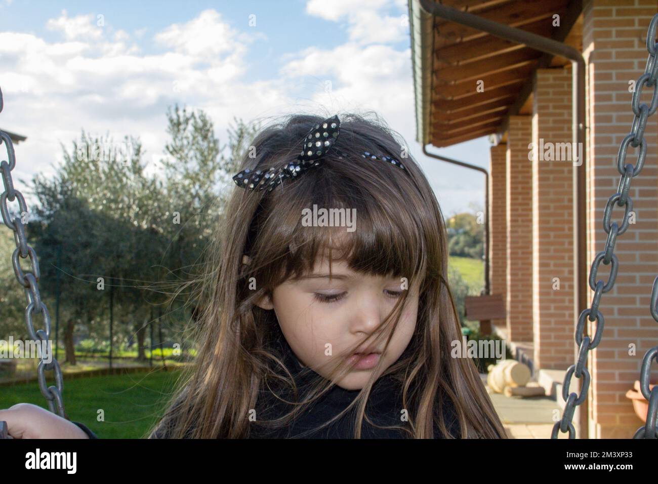 Image of an adorable little brunette girl with hair blowing in the wind ...