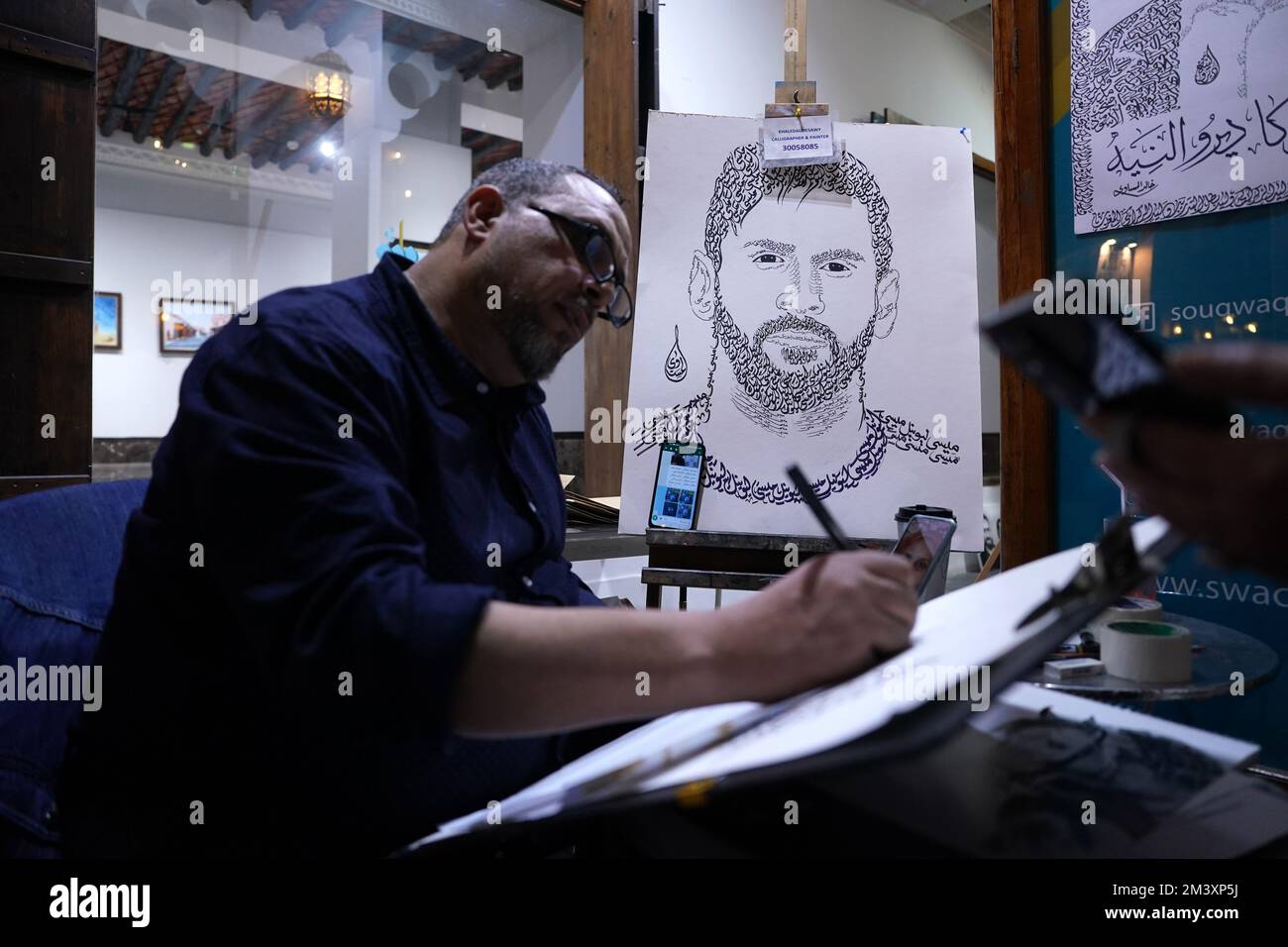 An artist at works with a drawing of Argentina's Lionel Messi in ...