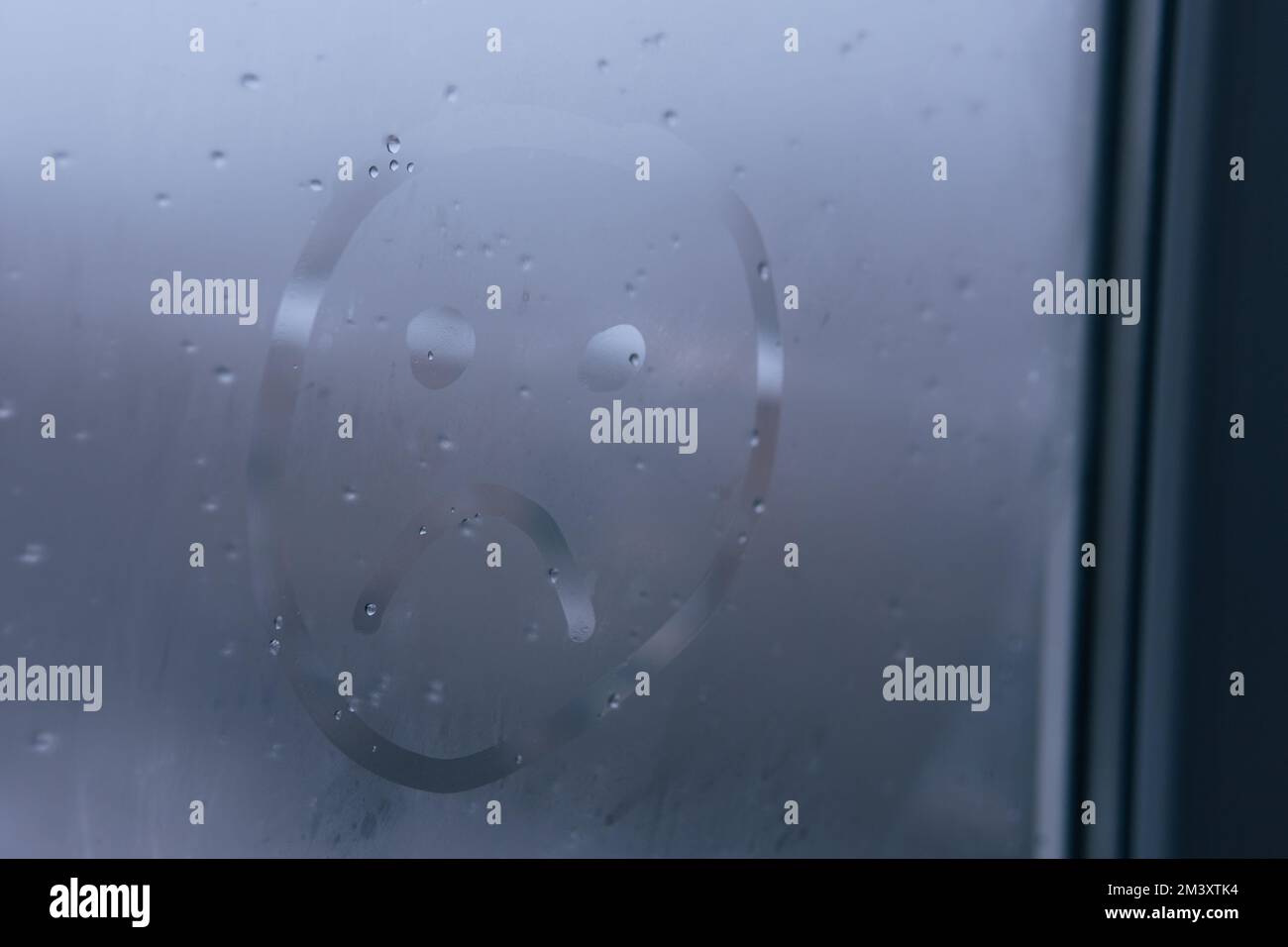 Unhappy, sad emoji on foggy glass window. Face sign close-up. Selective ...