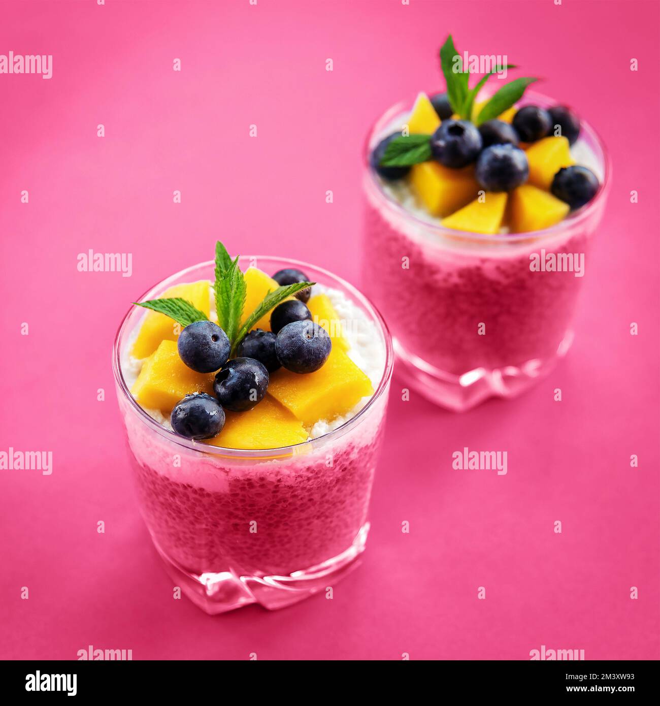 Two glasses of Chia pudding with coconut cream, mango and blueberry on ...