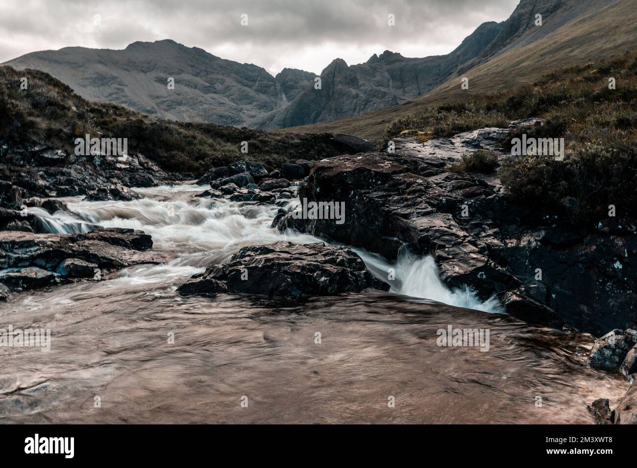 A horizontal shot from above the waterfall in woods under a dark cloudy ...