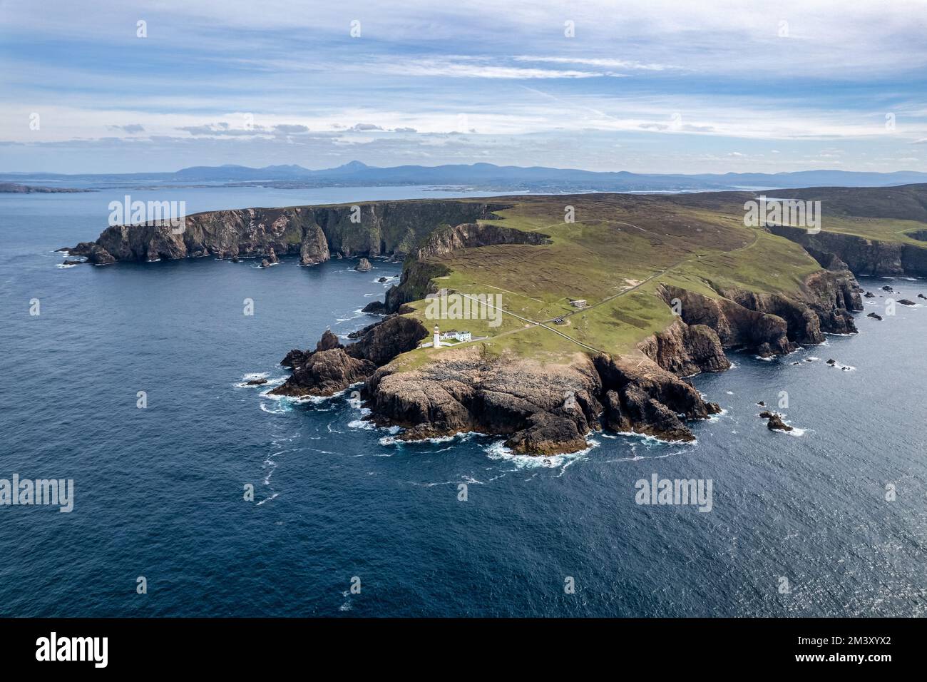 An aerial view of a lighthouse at the edge of a coastal cliff in ...