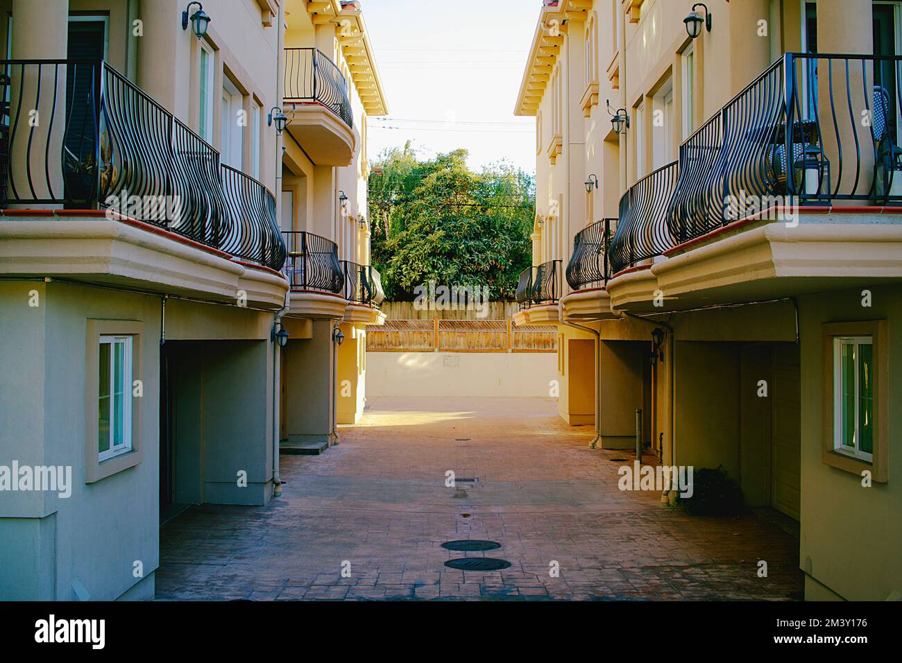 The narrow pathway between twin buildings with balconies on a sunny day ...