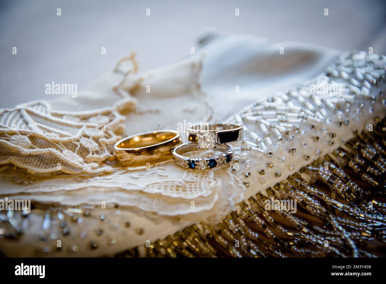 The wedding rings on a cream fabric decorated with glass beads against ...