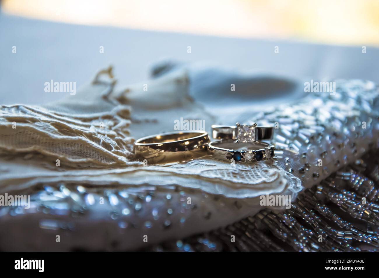 The wedding rings on a cream fabric decorated with glass beads against ...