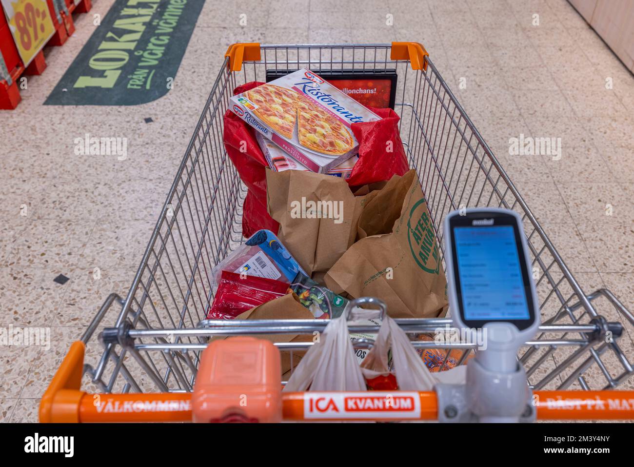 Close up view of grocery cart with scanner and purchased groceries in ...