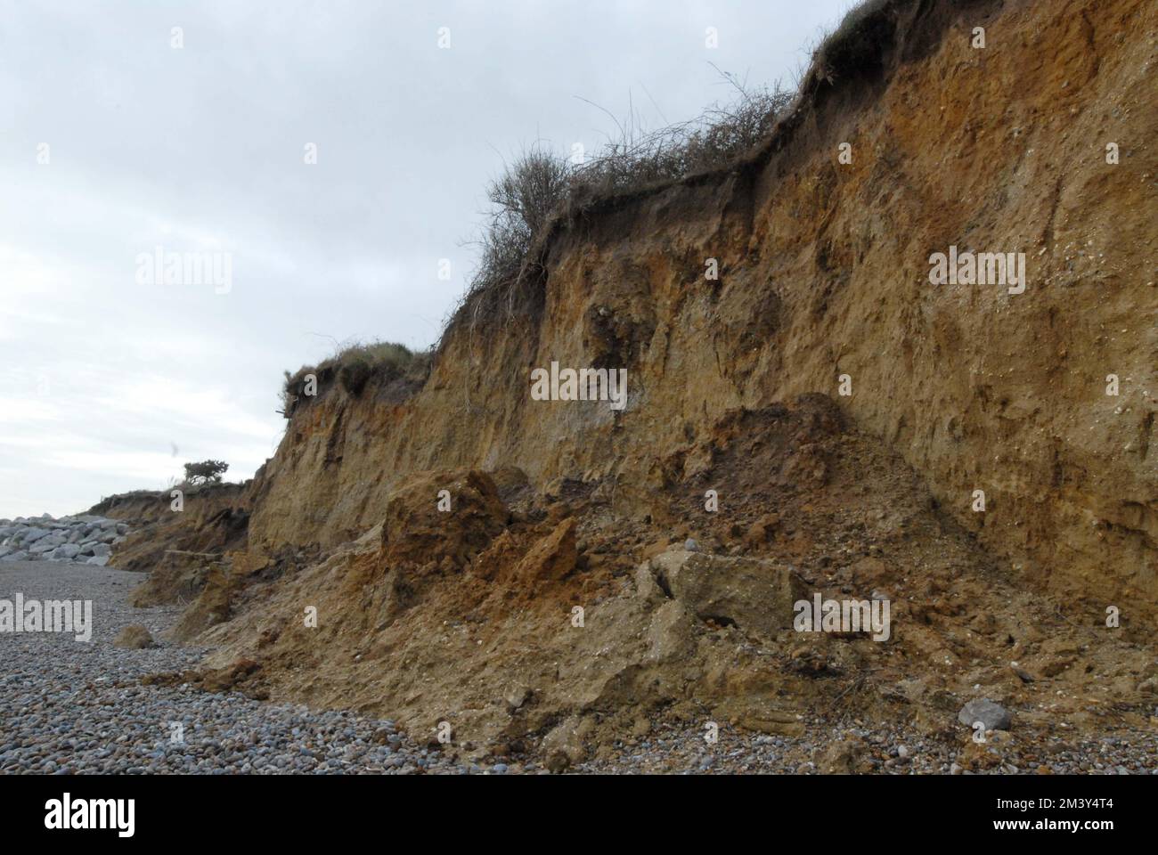Line of debris slumped from cliffs damaged by coastal erosion, with ...