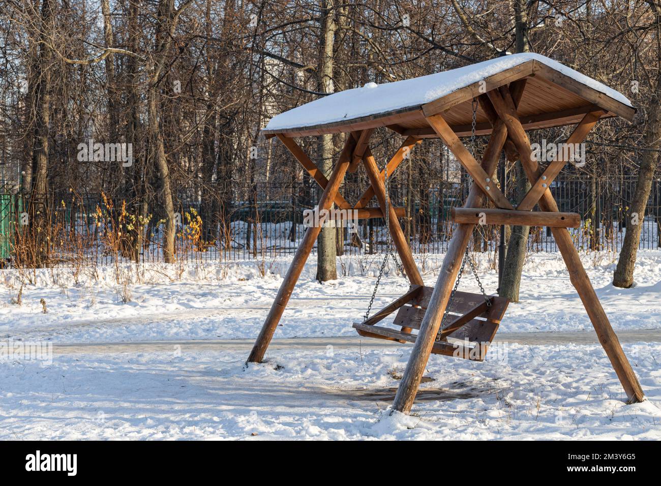 empty swing covered with snow in winter park. swing in the park in ...