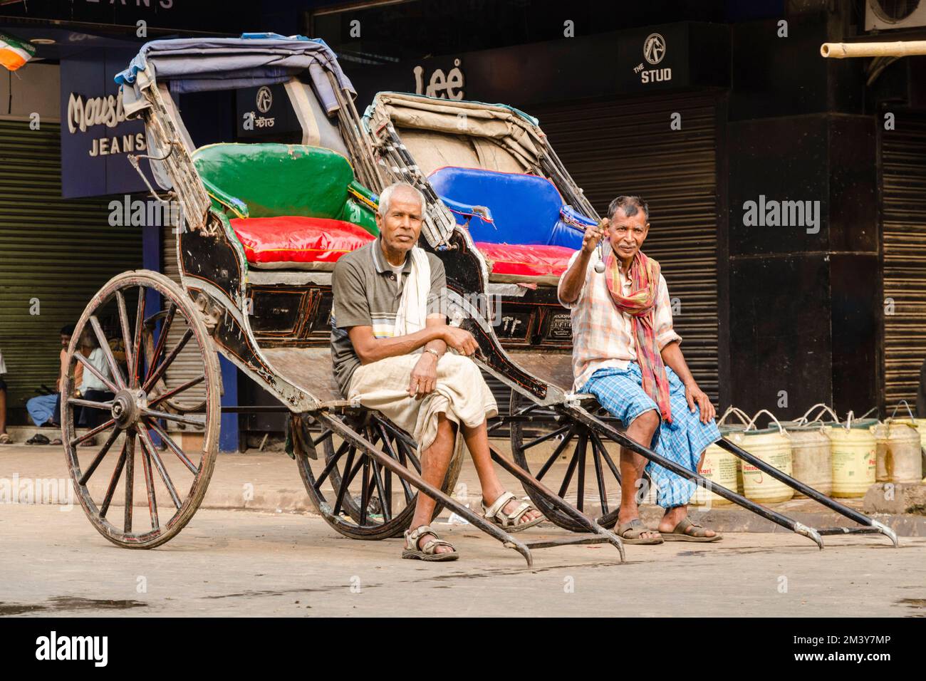 Two pull rikshaw kulis sitting on their rikshaws, waiting for customers ...