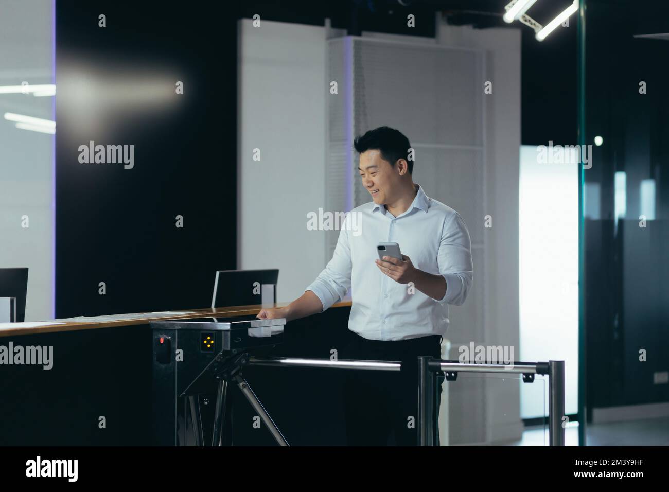 Young man Asian programmer, ceo, IT specialist enters office through electronic turnstile ...