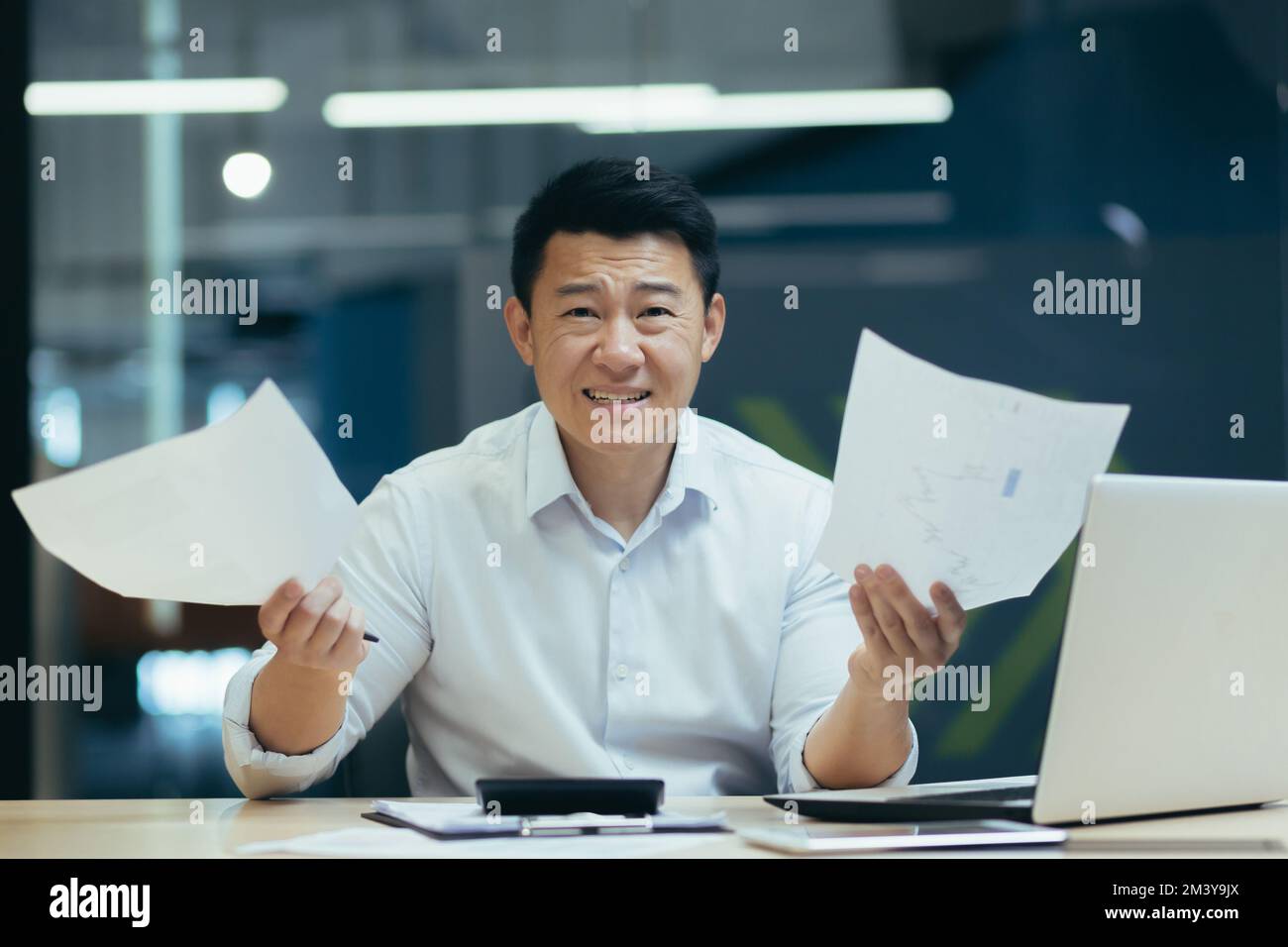 A worried young man, an Asian businessman, is sitting in the office at ...