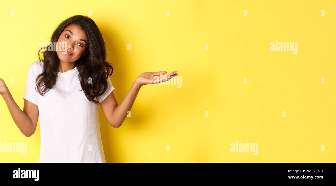 Portrait of clueless, beautiful african-american girl, shrugging and ...