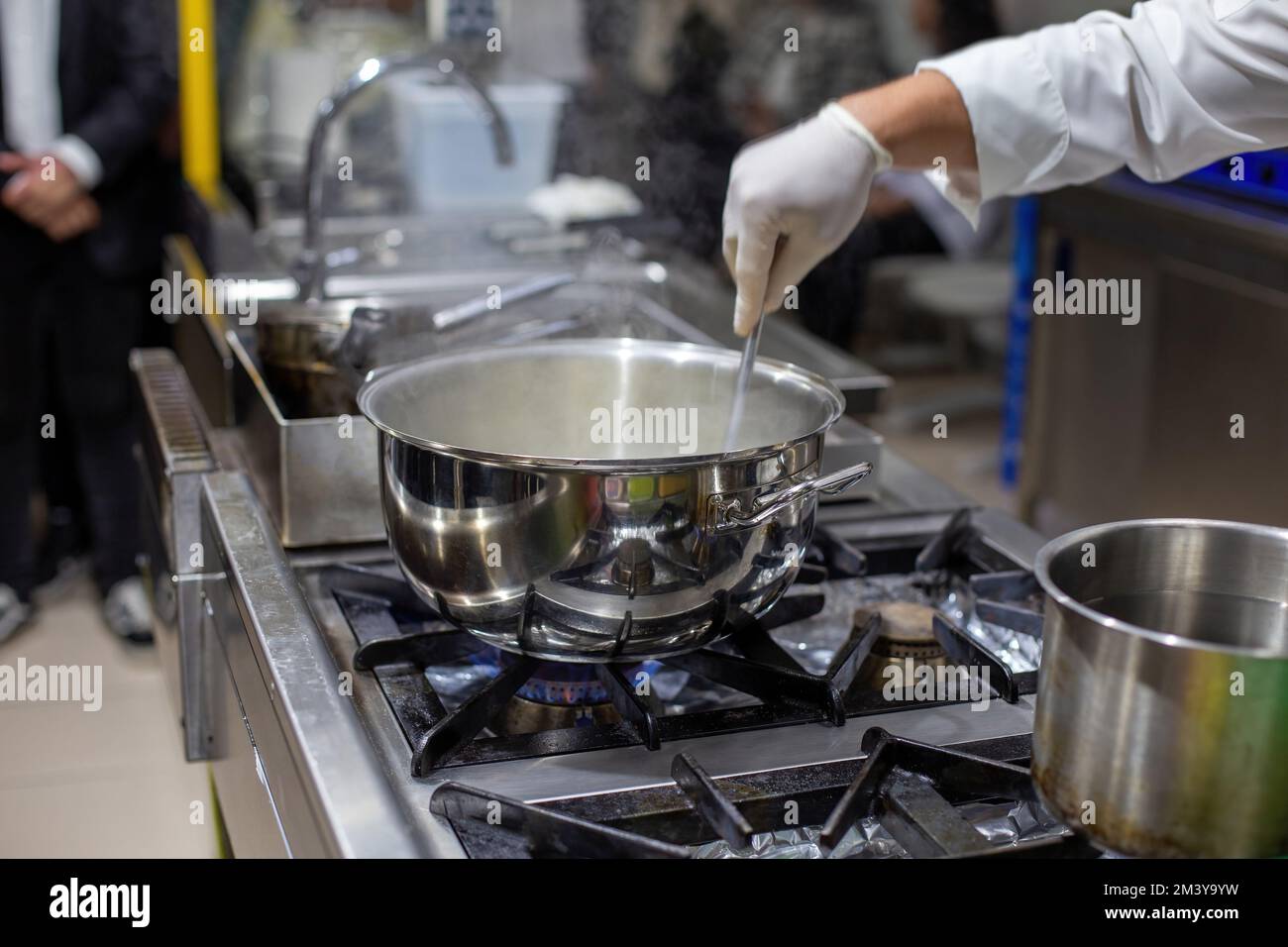 A cook stirring pots in the kitchen. Big pots in the kitchen Stock ...