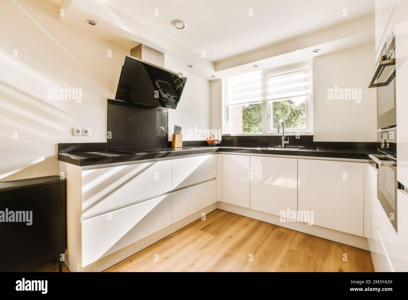 a modern kitchen with white cabinets and black counter tops on the ...