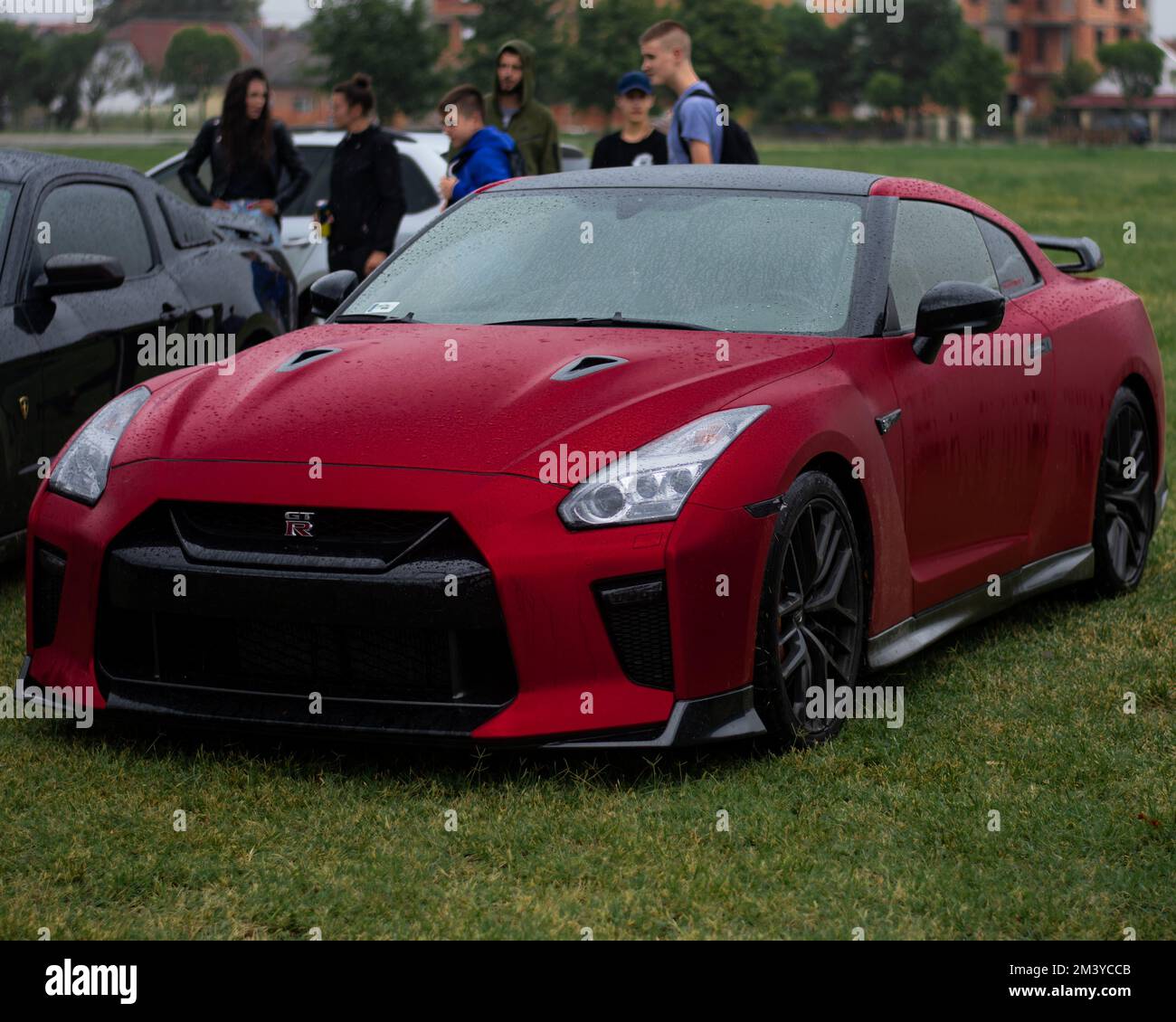 A wet red Nissan GT-R sports car at a car meet outdoors Stock Photo - Alamy