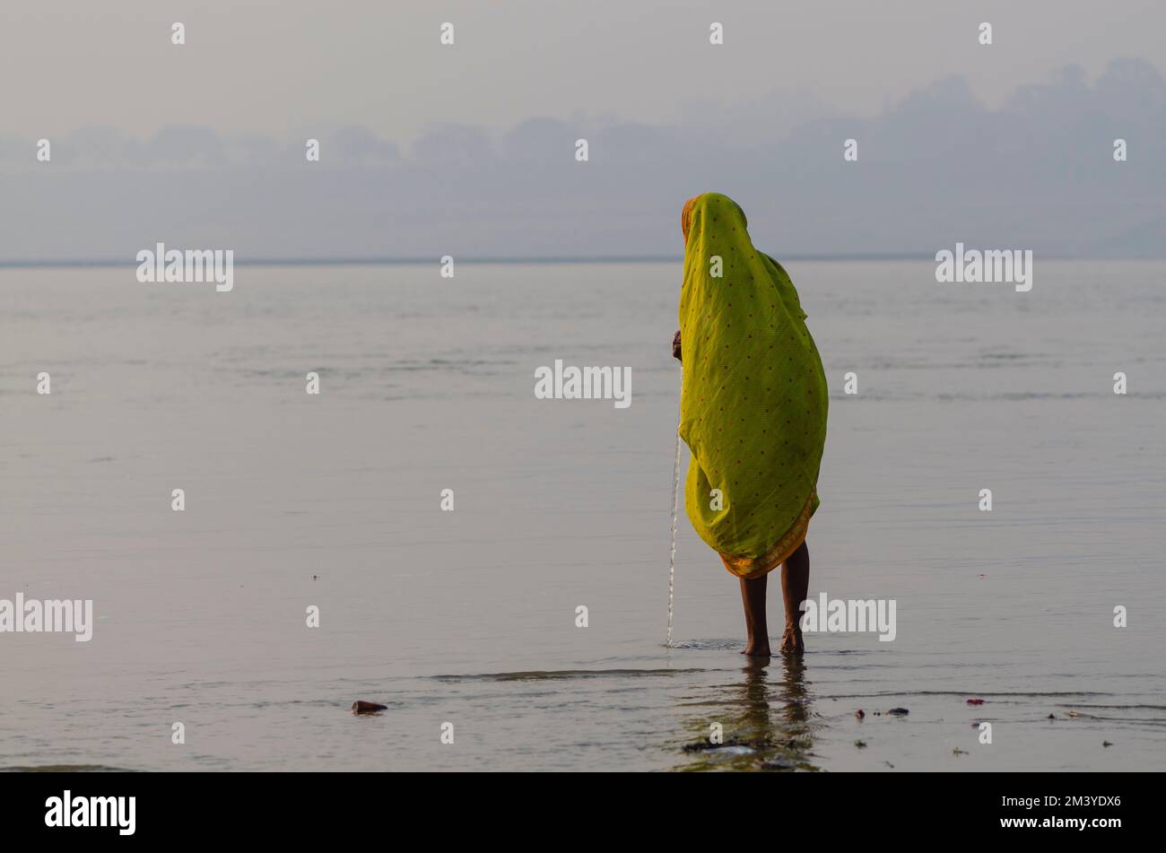 Single pilgrim lady standing in the water at Sangam, the confluence of ...