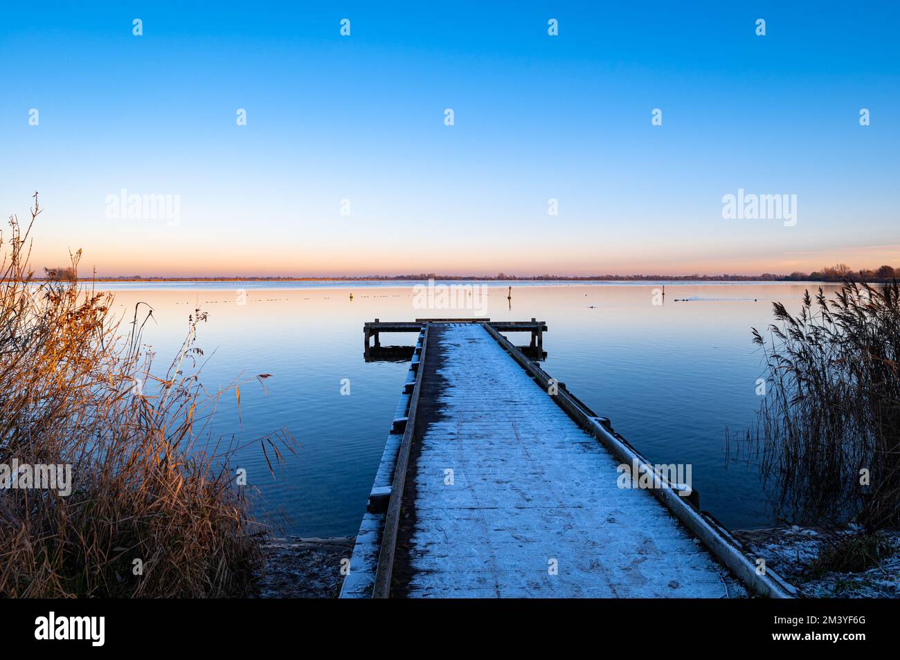 Snow covered jetty at lake "Reeuwijkse Plassen" in the Netherlands ...
