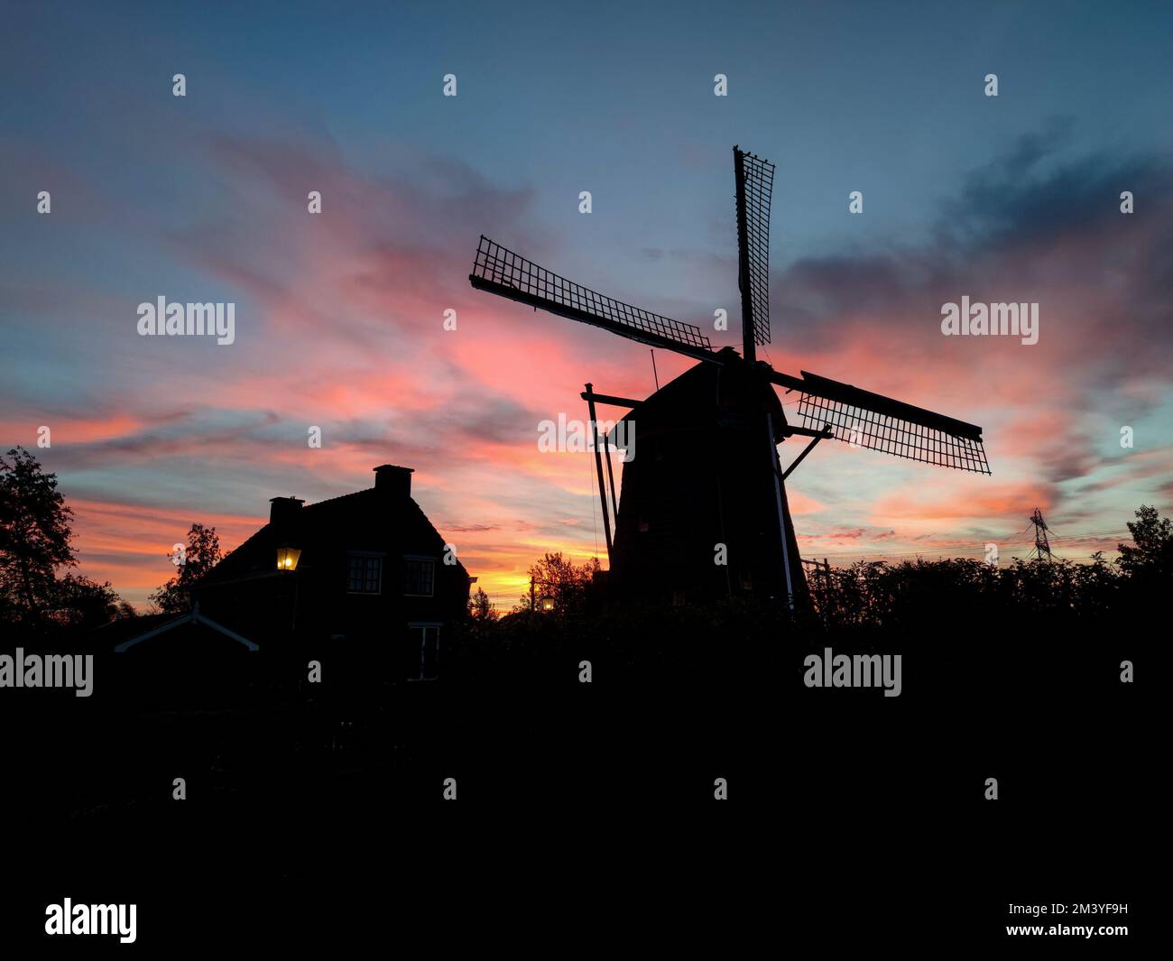 Silhouette of a traditional windmill during sunrise with pink clouds in ...