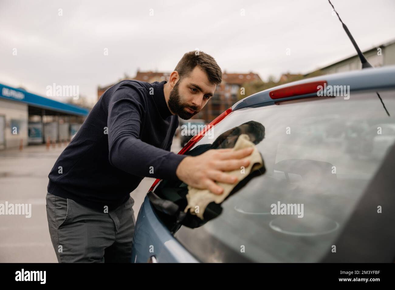 Portrait of a young man cleaning his car with a cloth Stock Photo - Alamy