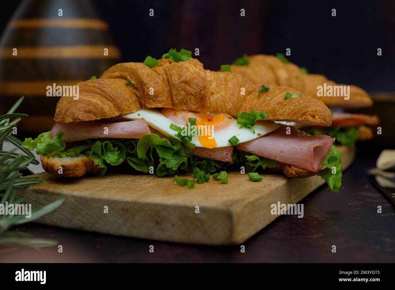 A closeup of a croissant sandwich with bacon and egg on a board Stock ...