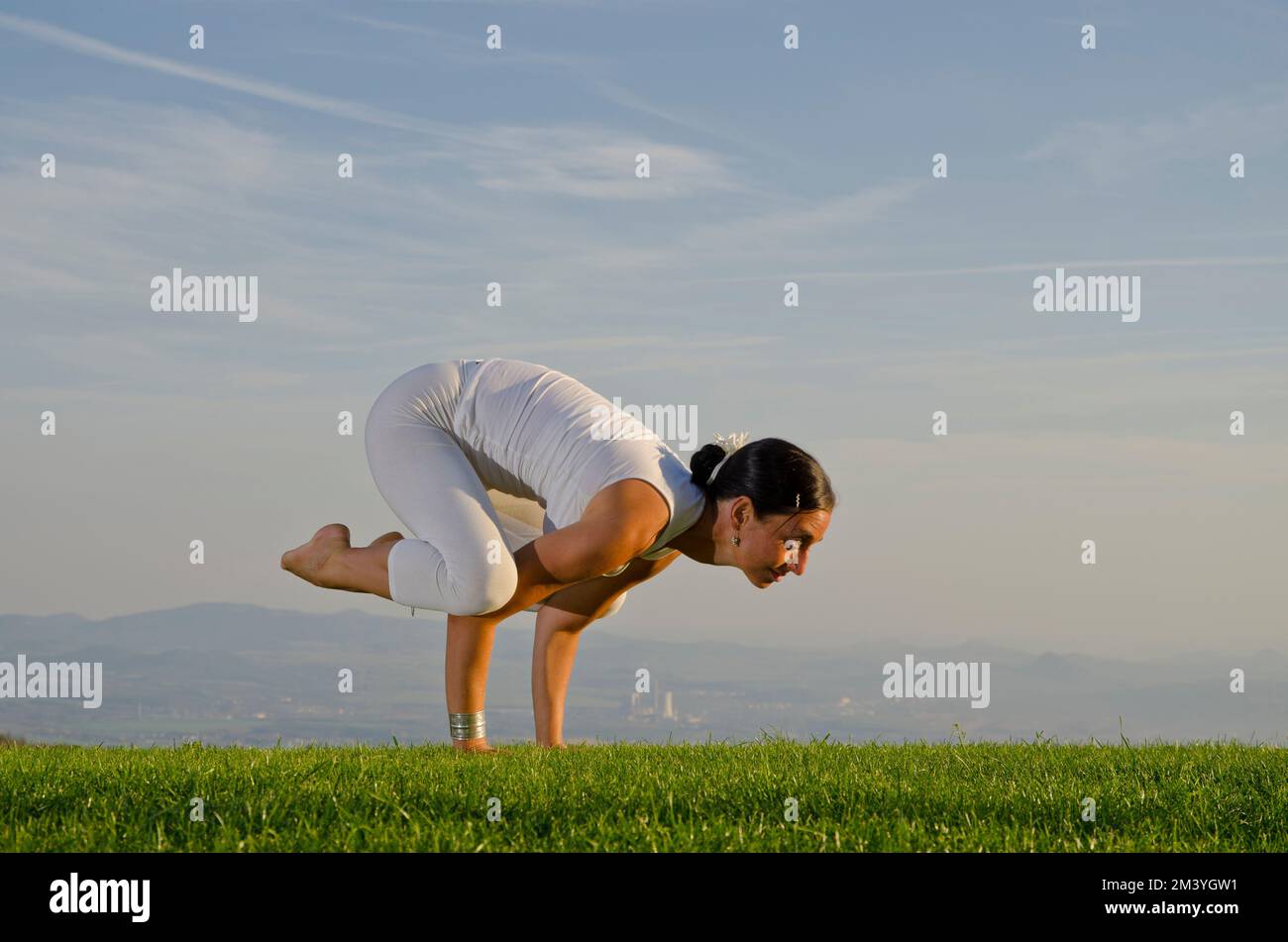 Young woman practising Hatha-Yoga outdoor, showing the pose kakasana ...