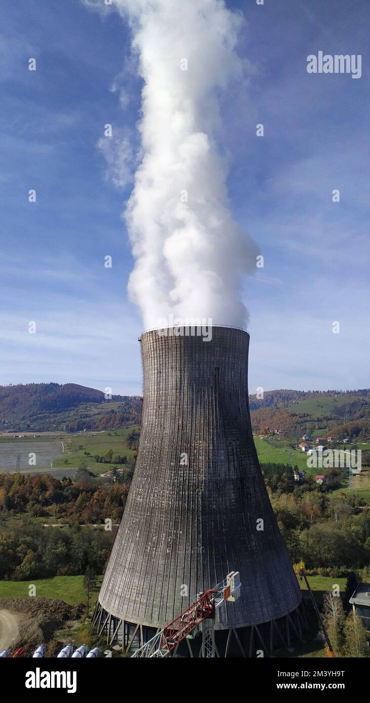 A nuclear power plant with plumes of smoke coming out of it against a ...