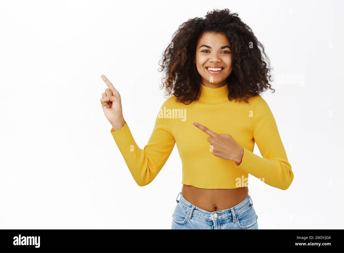 Smiling african american girl with curly hair, pointing fingers left at ...